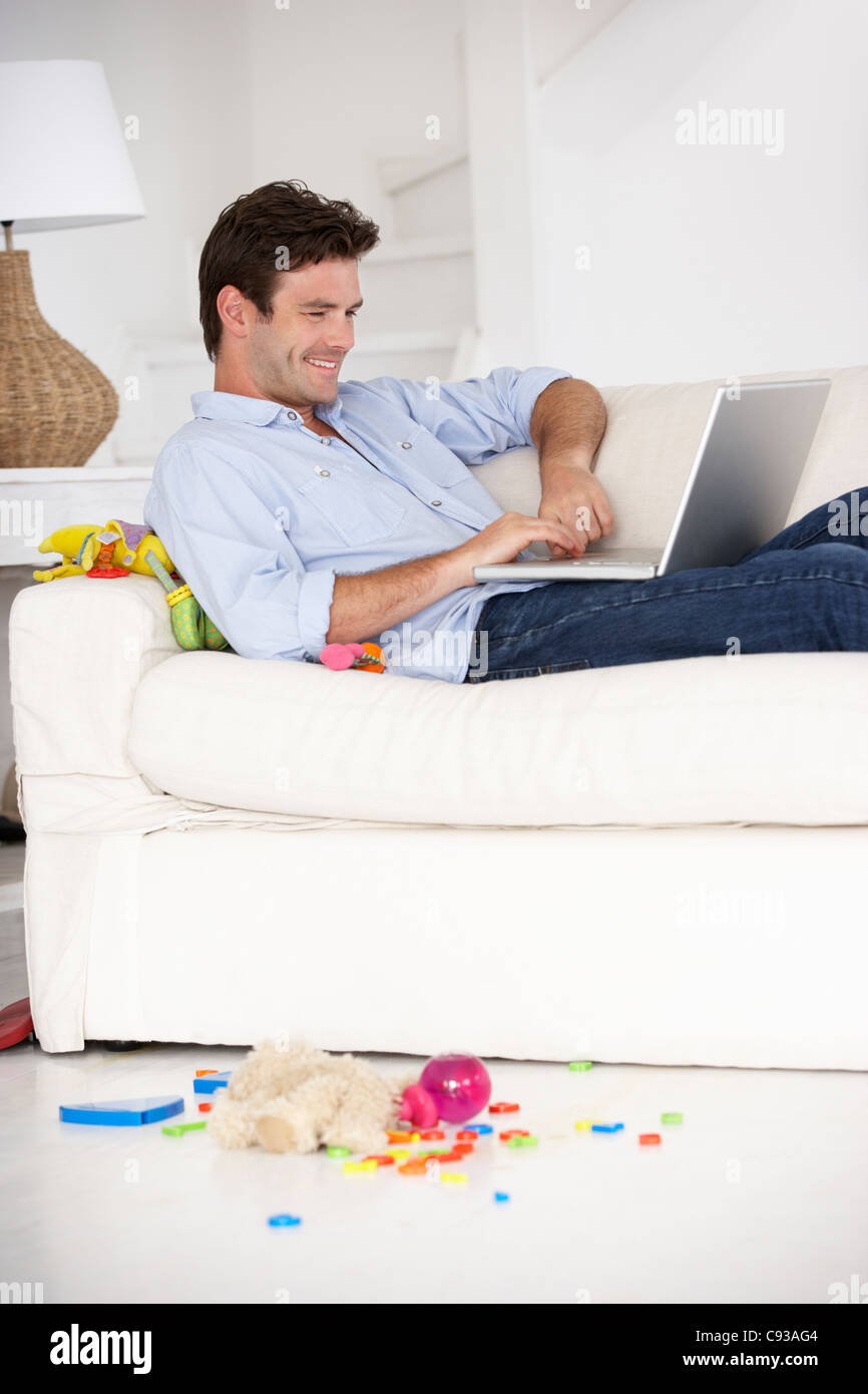 Busy father working on laptop Stock Photo - Alamy
