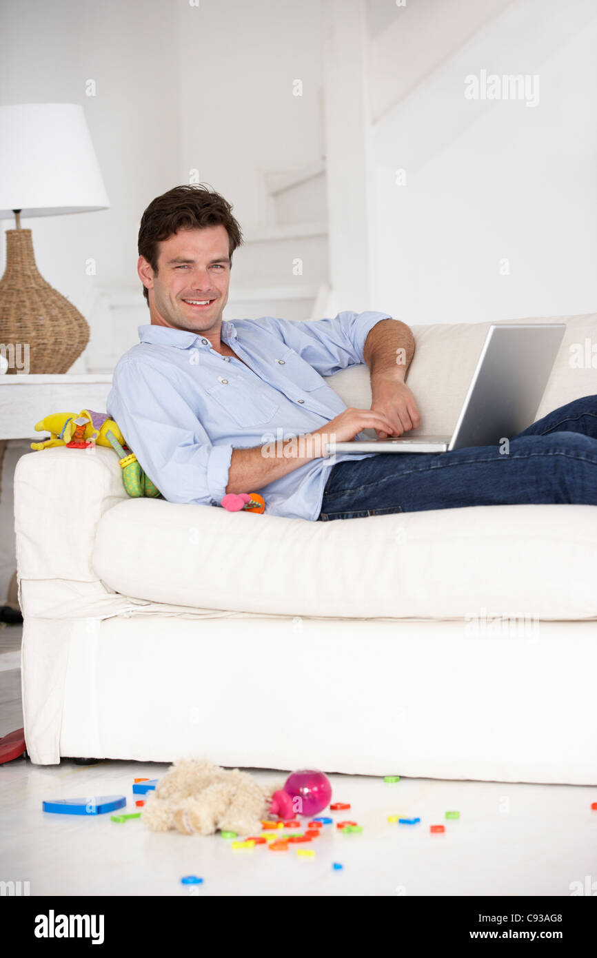Busy father working on laptop Stock Photo - Alamy