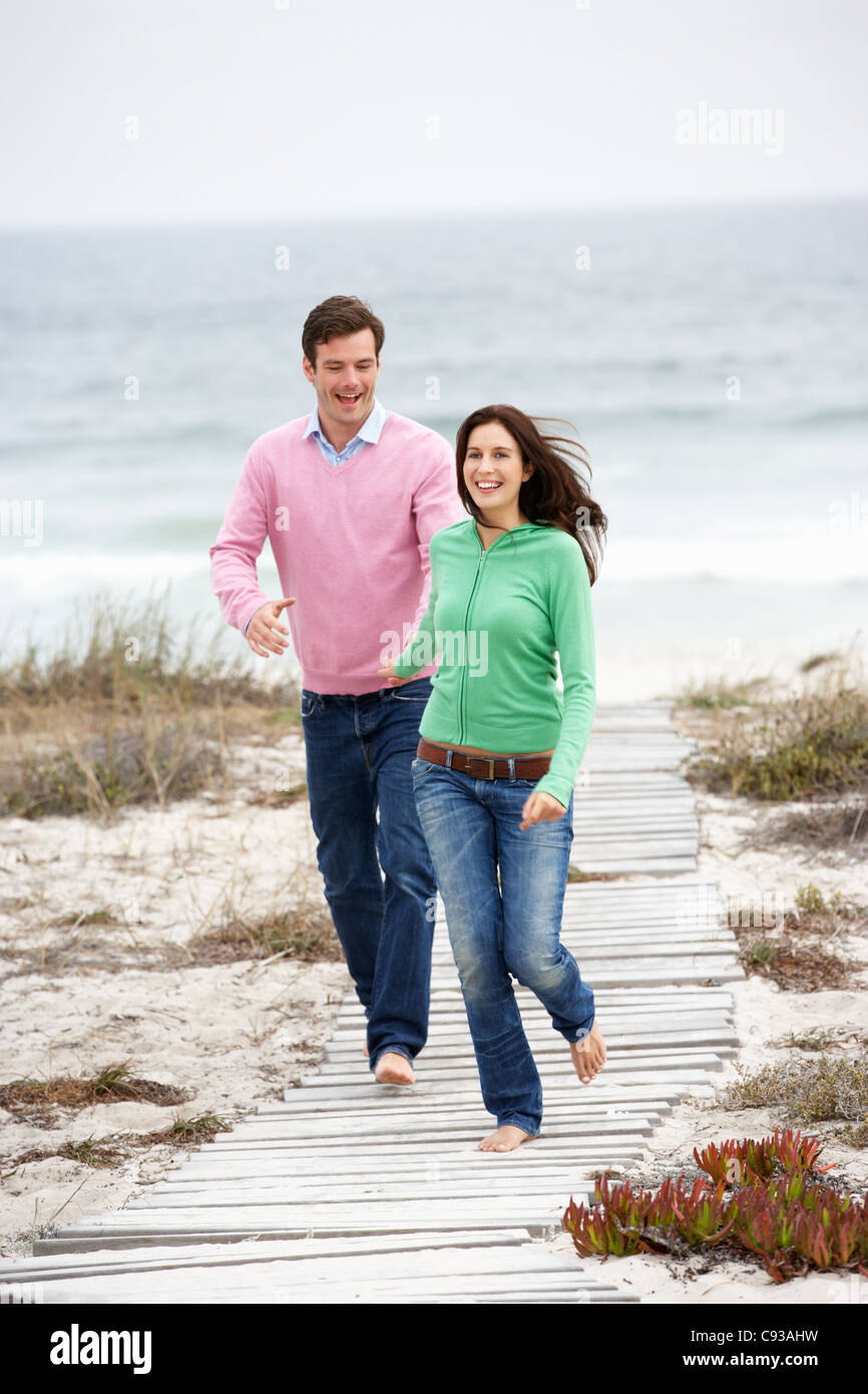 Couple running along beach path Stock Photo - Alamy