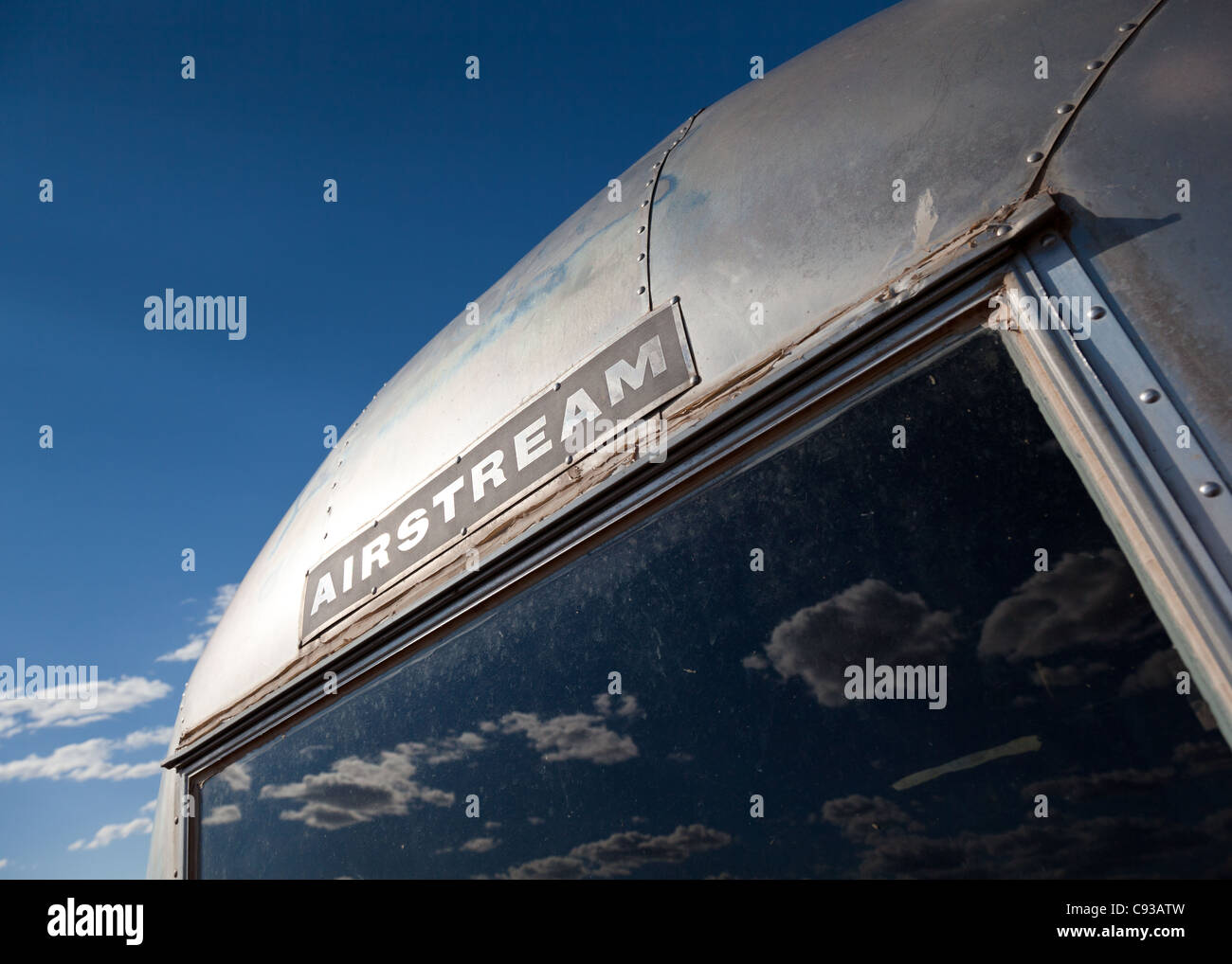 Rear section of a silver Airstream caravan with blue sky and clouds ...