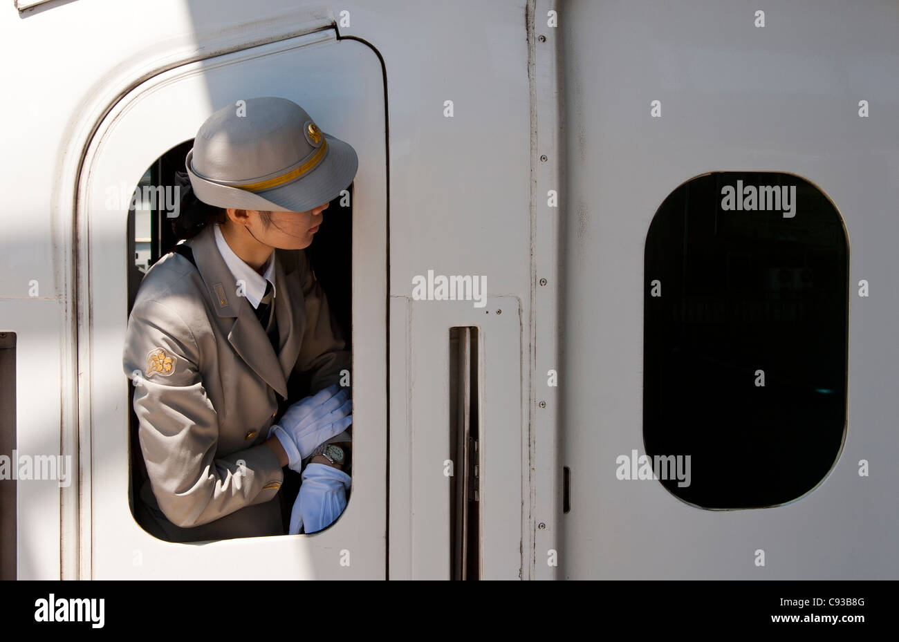 A female guard looks checks her watch looking out the window of a JR ...