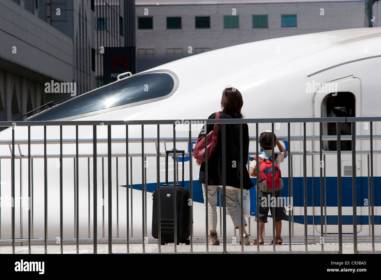 A mother and son watch a JR 700 class shinkansen (bullet train) at ...