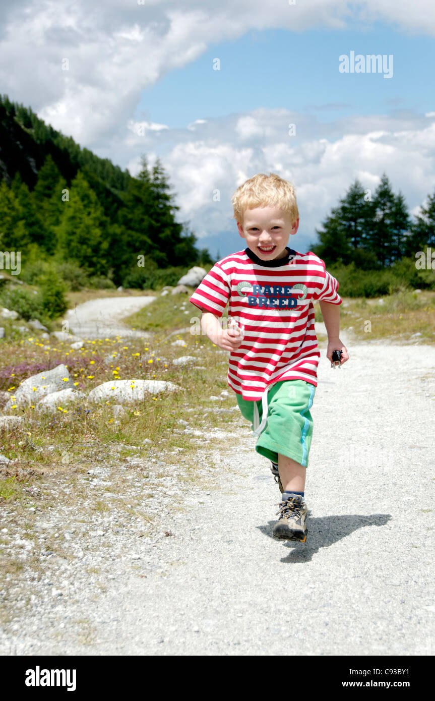 A young boy running along a mountain track Stock Photo - Alamy