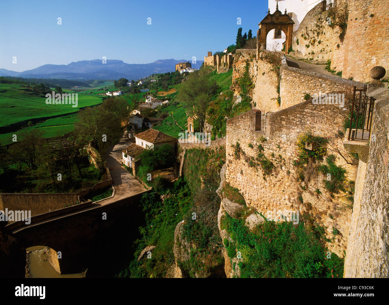 Stone walls under hillside village of Ronda overlooking fields in ...