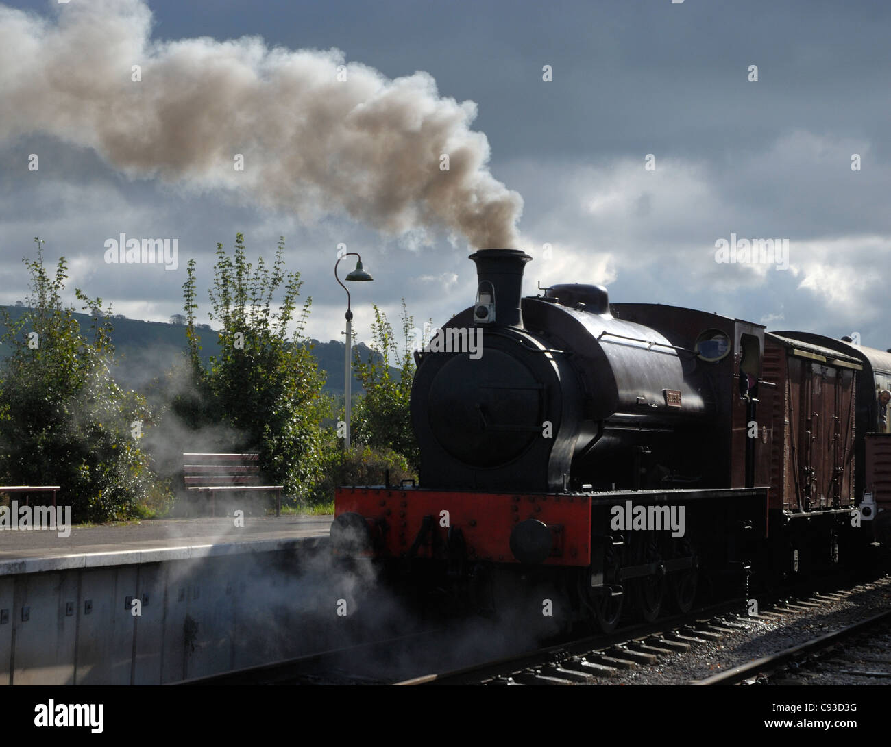 Steam locomotive back lit by the sun waiting to leave with a goods ...