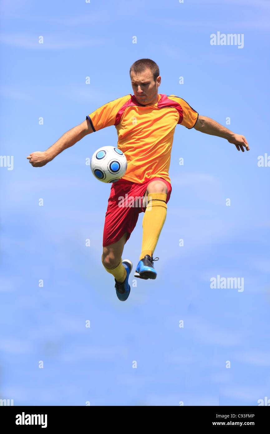 Soccer player kicking the ball while jumping Stock Photo - Alamy
