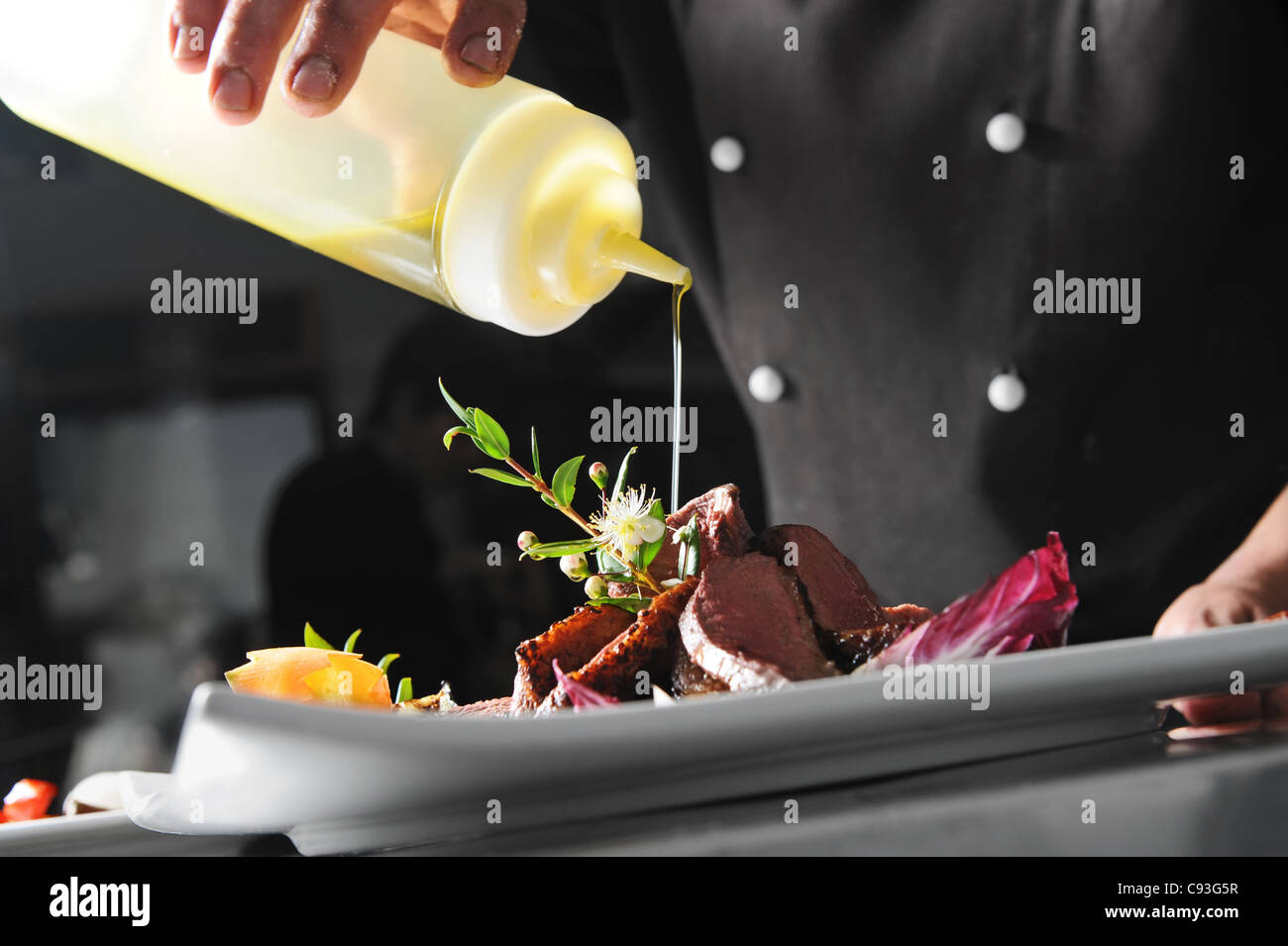cook decorating a dish in a restaurant kitchen Stock Photo - Alamy