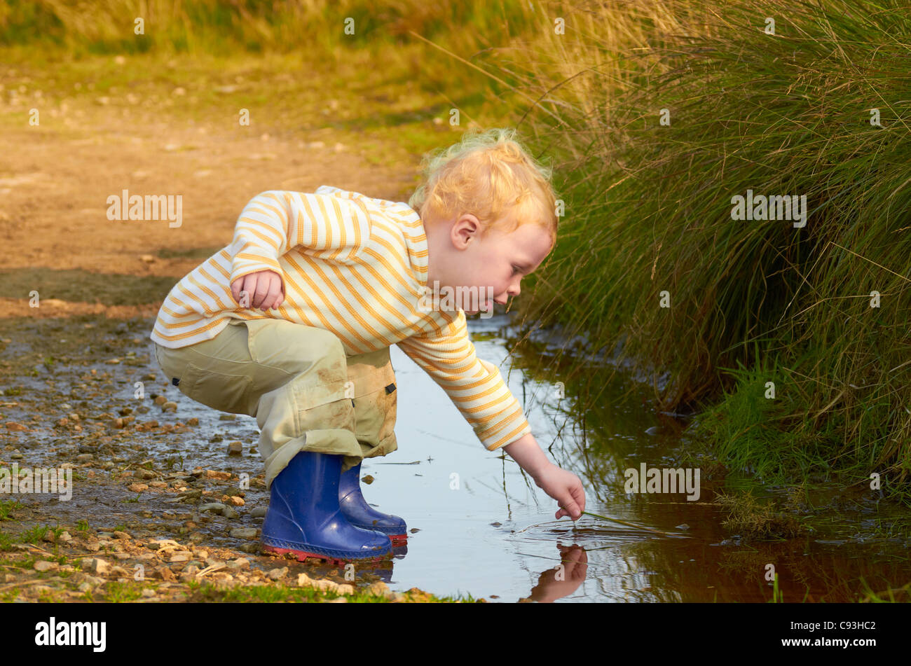Boy playing in puddle and water Stock Photo - Alamy