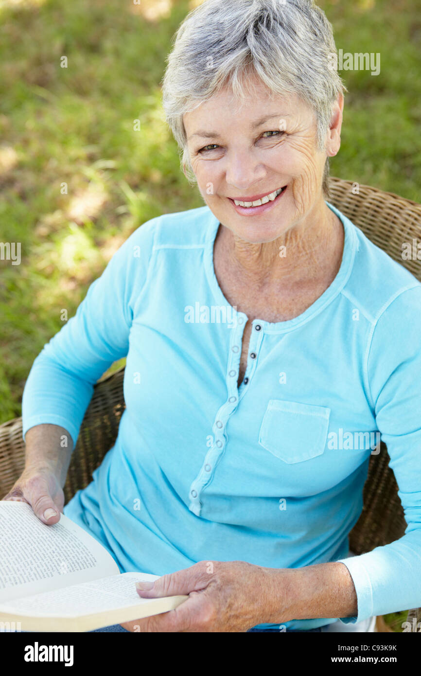 Senior woman reading book outdoors Stock Photo - Alamy