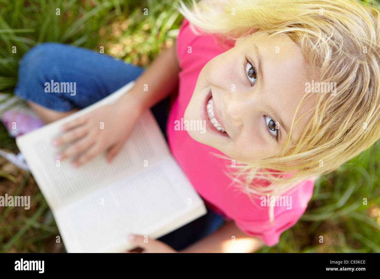 Little girl reading book outdoors Stock Photo - Alamy
