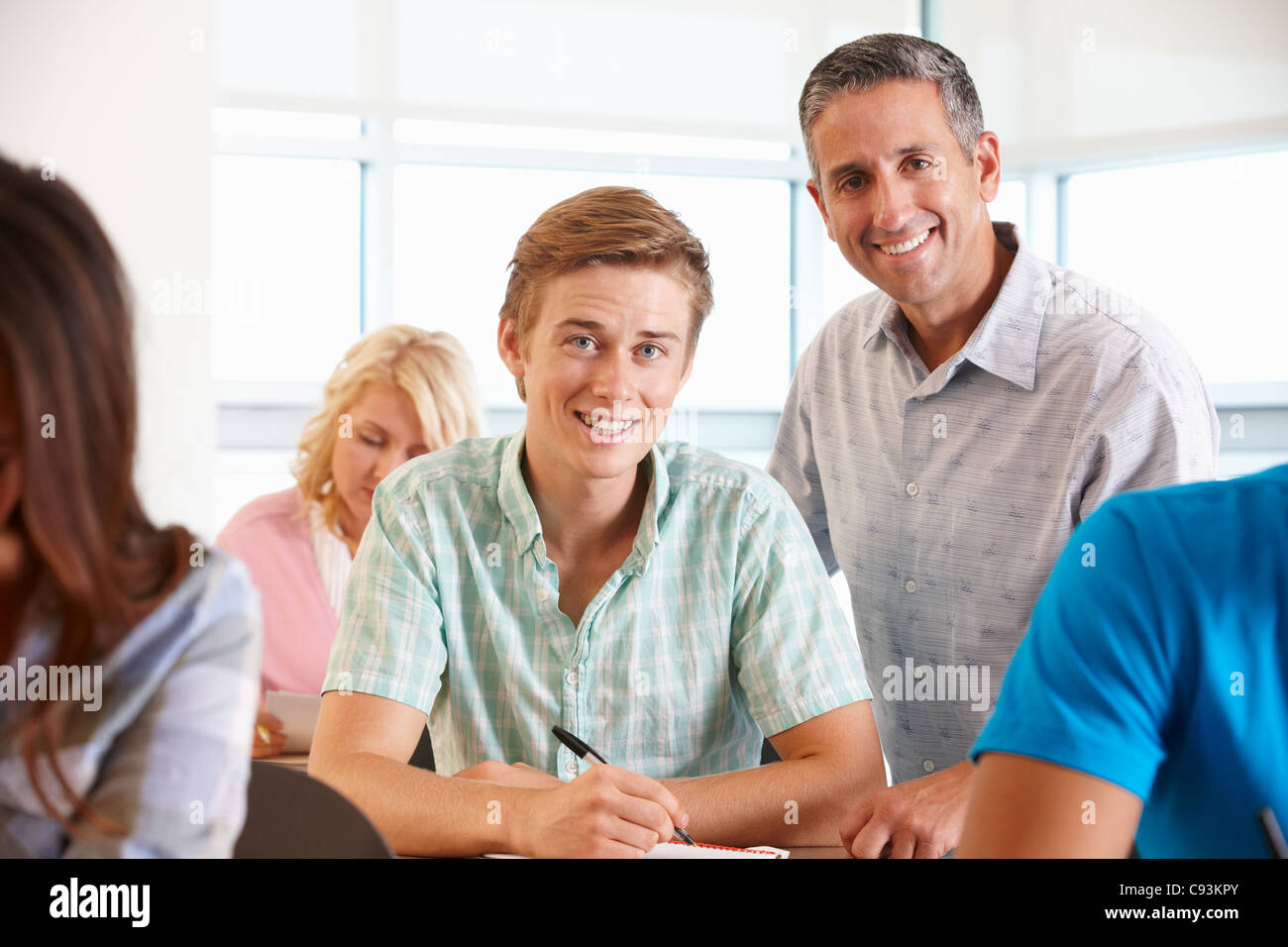 Tutor helping student in class Stock Photo - Alamy