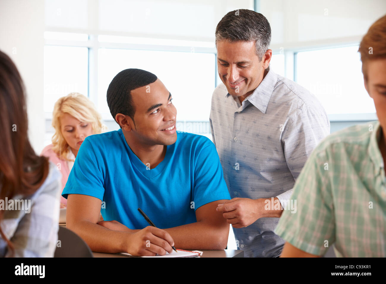 Tutor helping student in class Stock Photo - Alamy