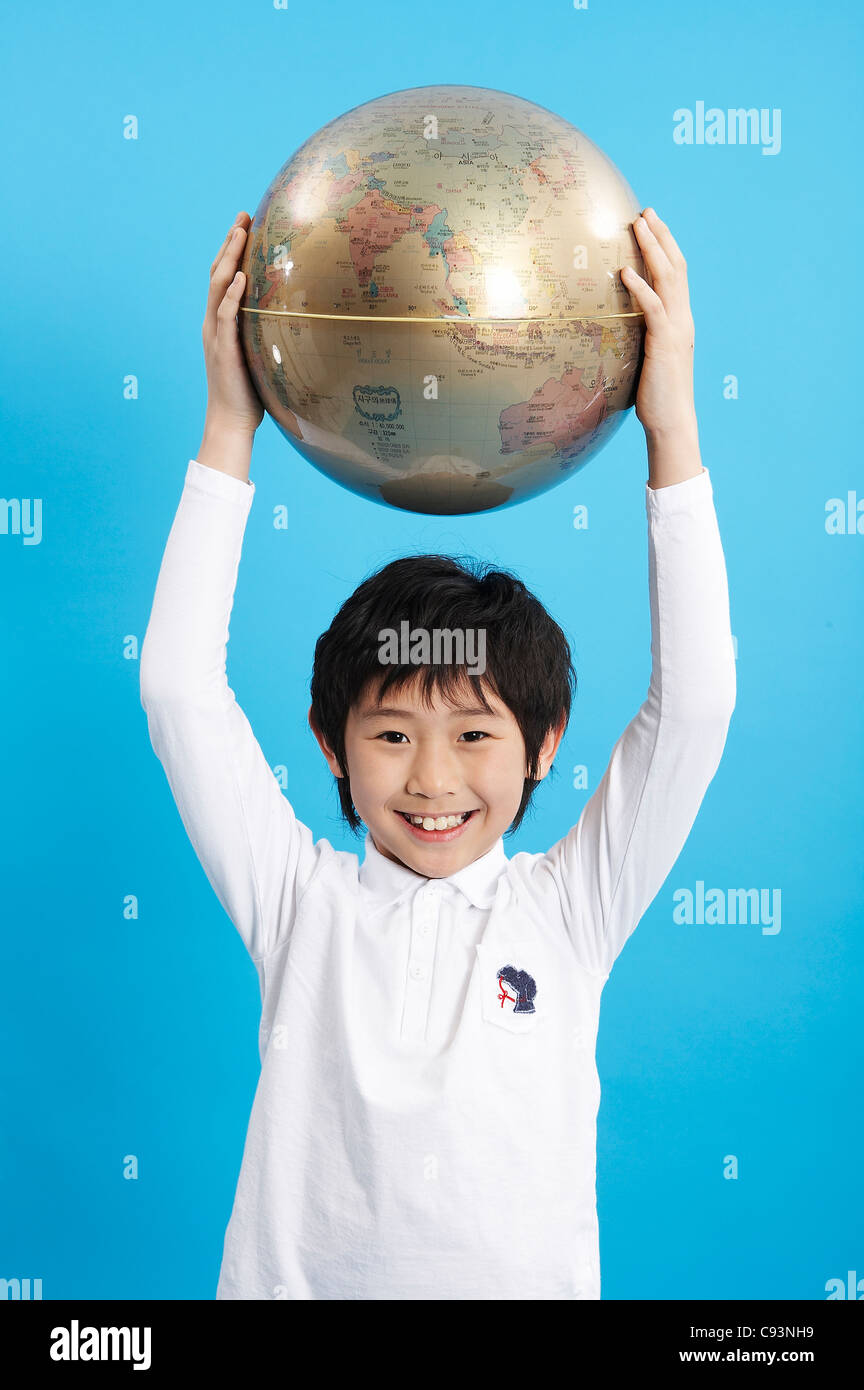 Portrait of a boy holding a globe over head Stock Photo - Alamy