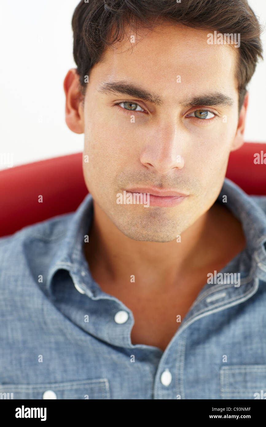 Young man sitting in red chair Stock Photo - Alamy