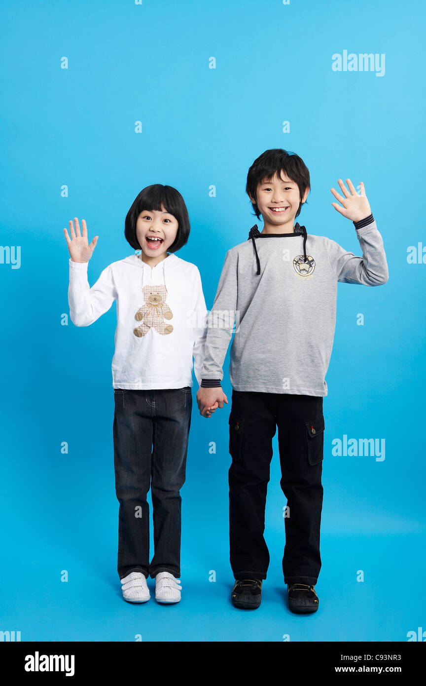 Boy and girl raising another hand with holding a hand, studio shot ...
