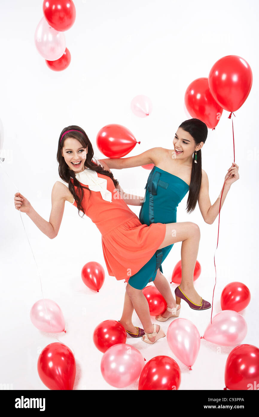 Two women hugging each other holding balloons in studio, smiling ...