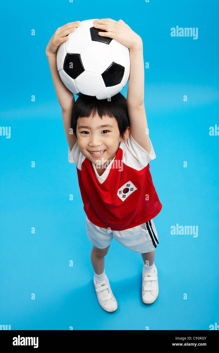 Boy in soccer uniform holding football in hand Stock Photo - Alamy