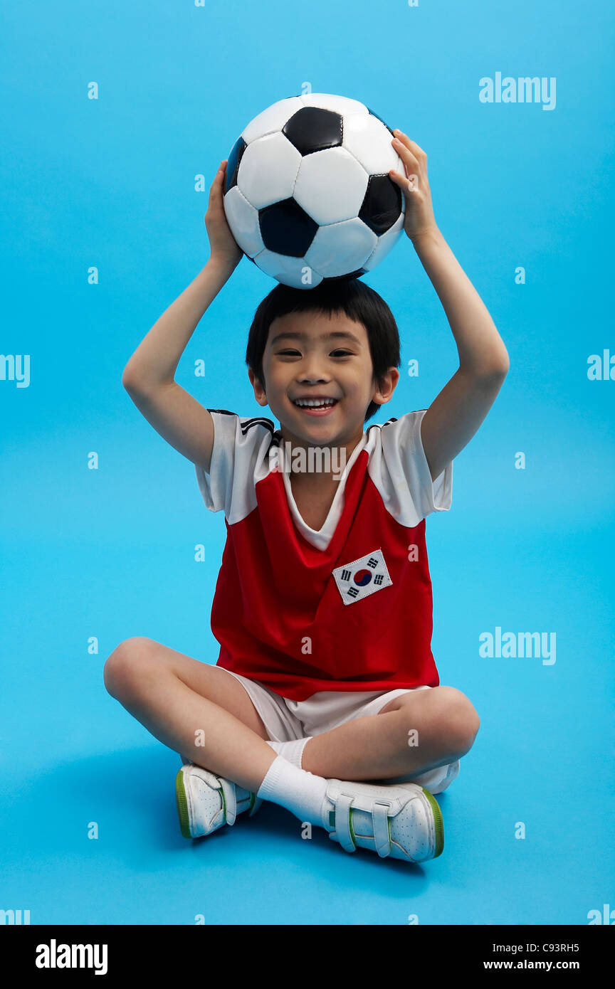 Boy in soccer uniform holding football on head Stock Photo - Alamy