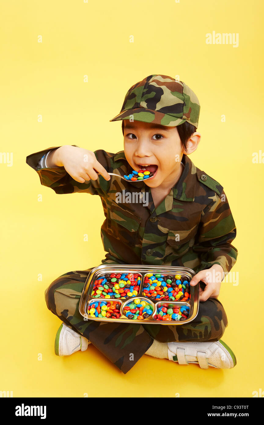 Portrait of boy in army uniform eating candy Stock Photo - Alamy