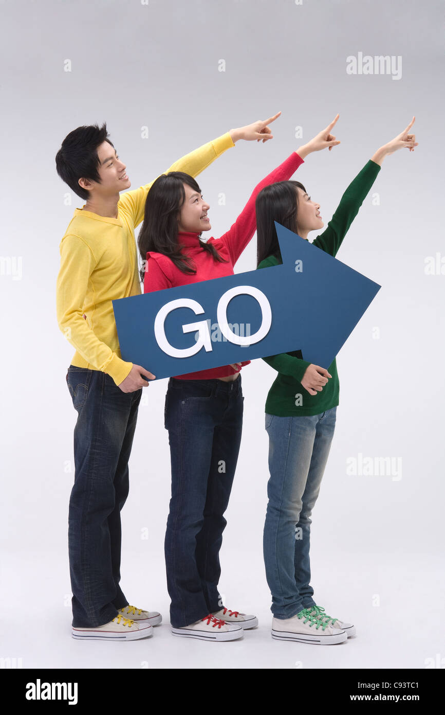 Portrait of three friends holding arrow sign Stock Photo - Alamy