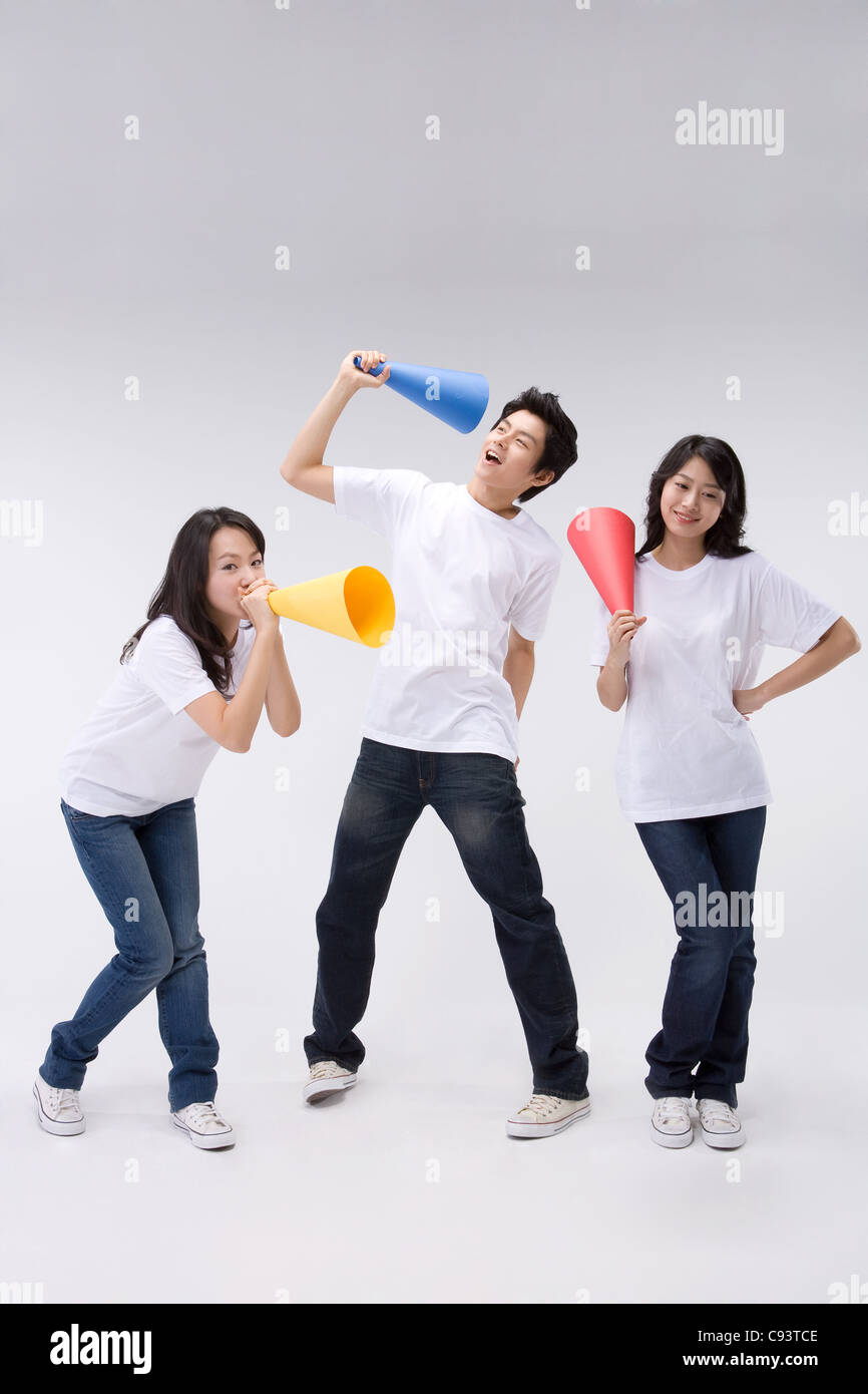 Portrait of three friends holding megaphone, studio shot Stock Photo ...