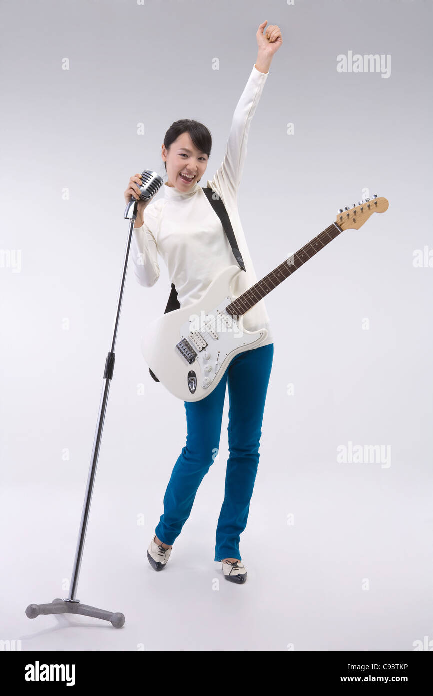 Portrait of young woman playing guitar with singing song in mike Stock ...