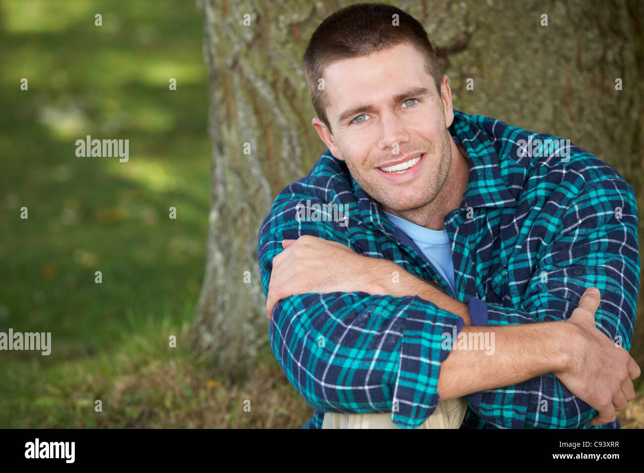 Man sitting against tree trunk hi-res stock photography and images - Alamy