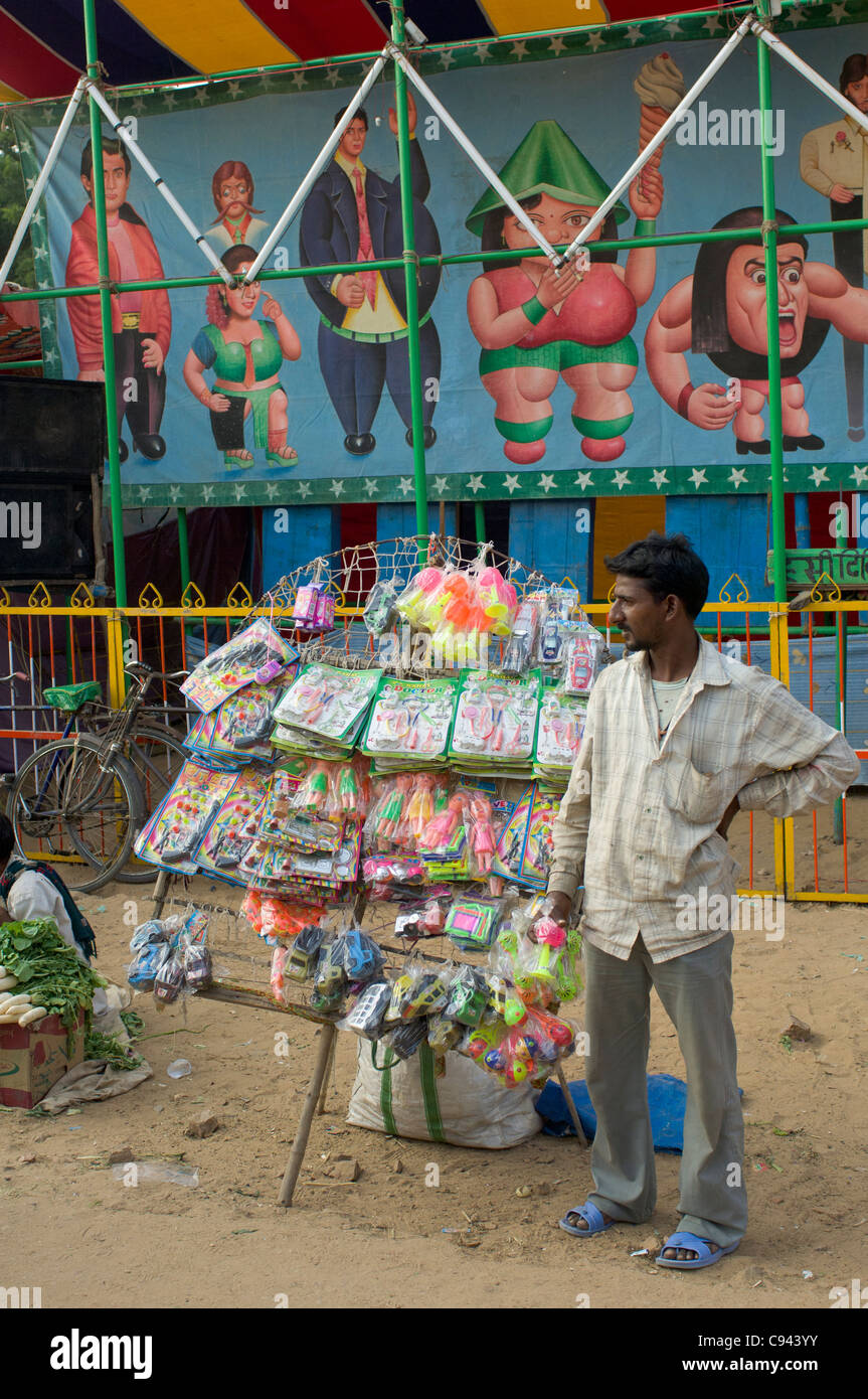 Man selling cheap plastic toys, in front of a fairground freak show ...