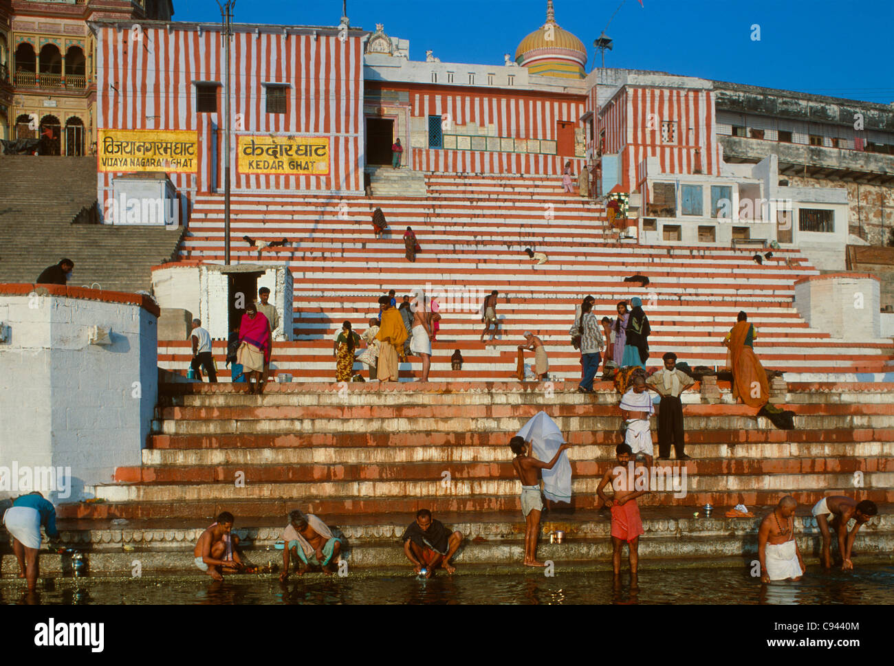 Pilgrims bathing on the brightly painted steps of Kedar Ghat, on the ...