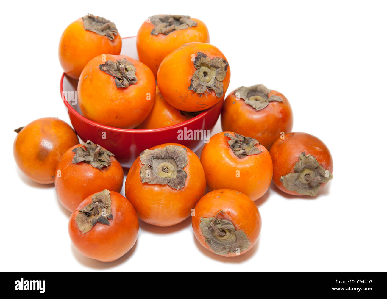 Red juicy persimmons isolated on white background. Laying in red plate ...