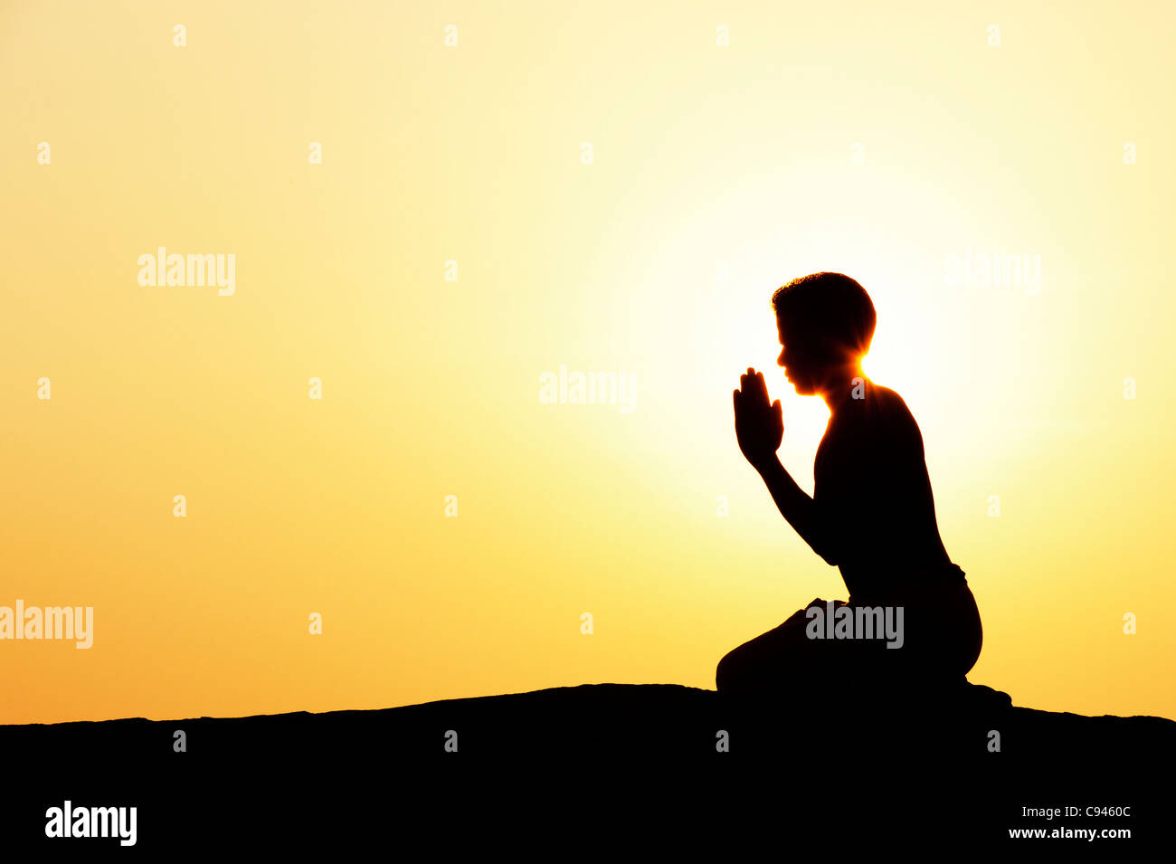 Indian man offering prayers to the sun at sunset. Silhouette. India ...