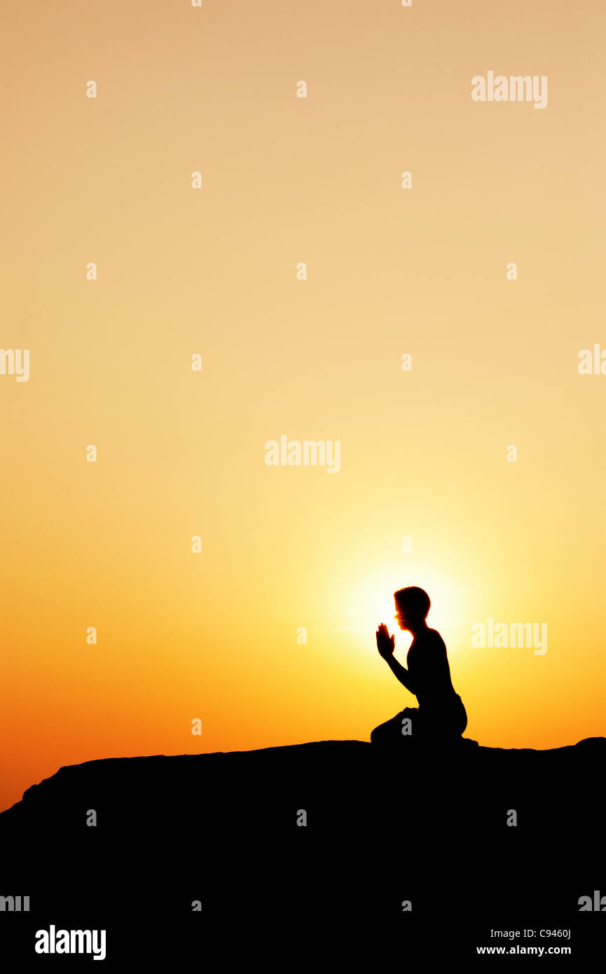 Indian man offering prayers to the sun at sunset. Silhouette. India ...