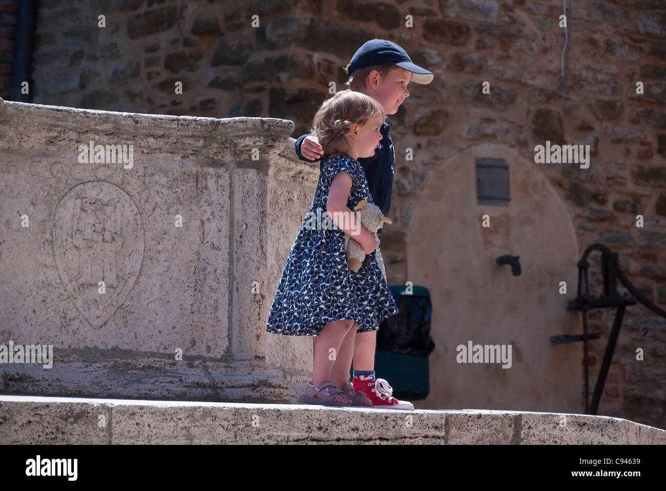 Two very young Italian children stand by a fountain with the girl ...