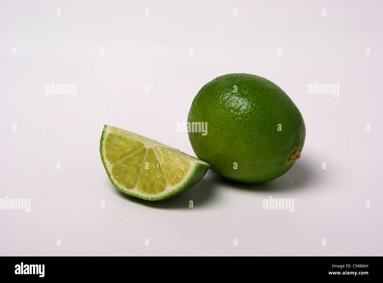 A whole lime sits beside a quarter piece of Lime Stock Photo - Alamy