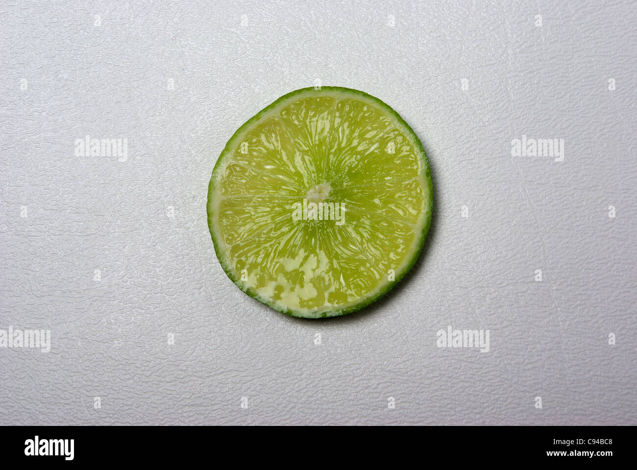 A slice of lime sits on a white background Stock Photo - Alamy