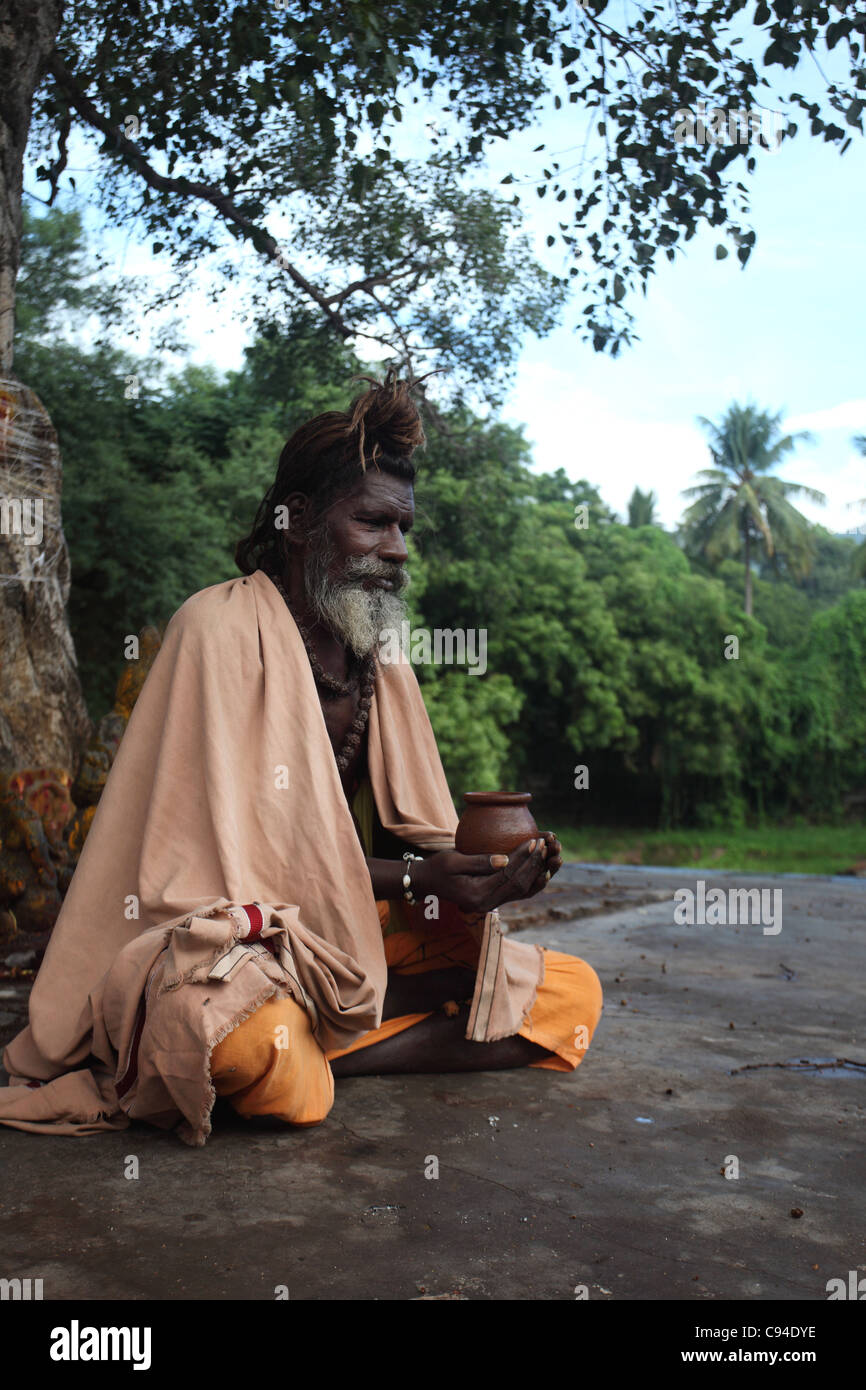 Sadhu sitting at a holy tree with statues of Hindu gods Tamil Nadu ...