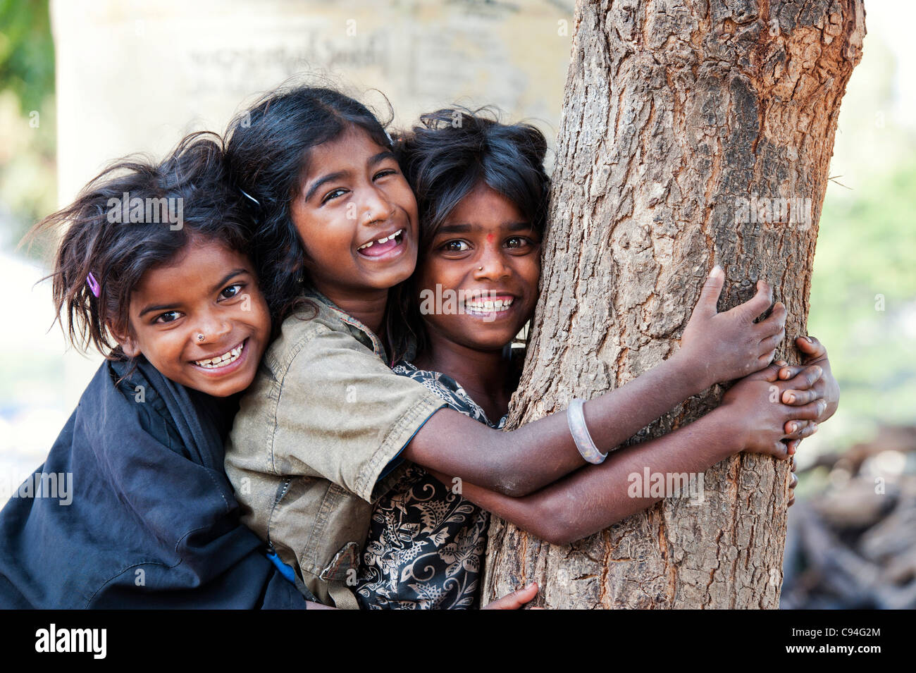Poor Indian nomadic beggar girls laughing whilst hugging a tree and ...
