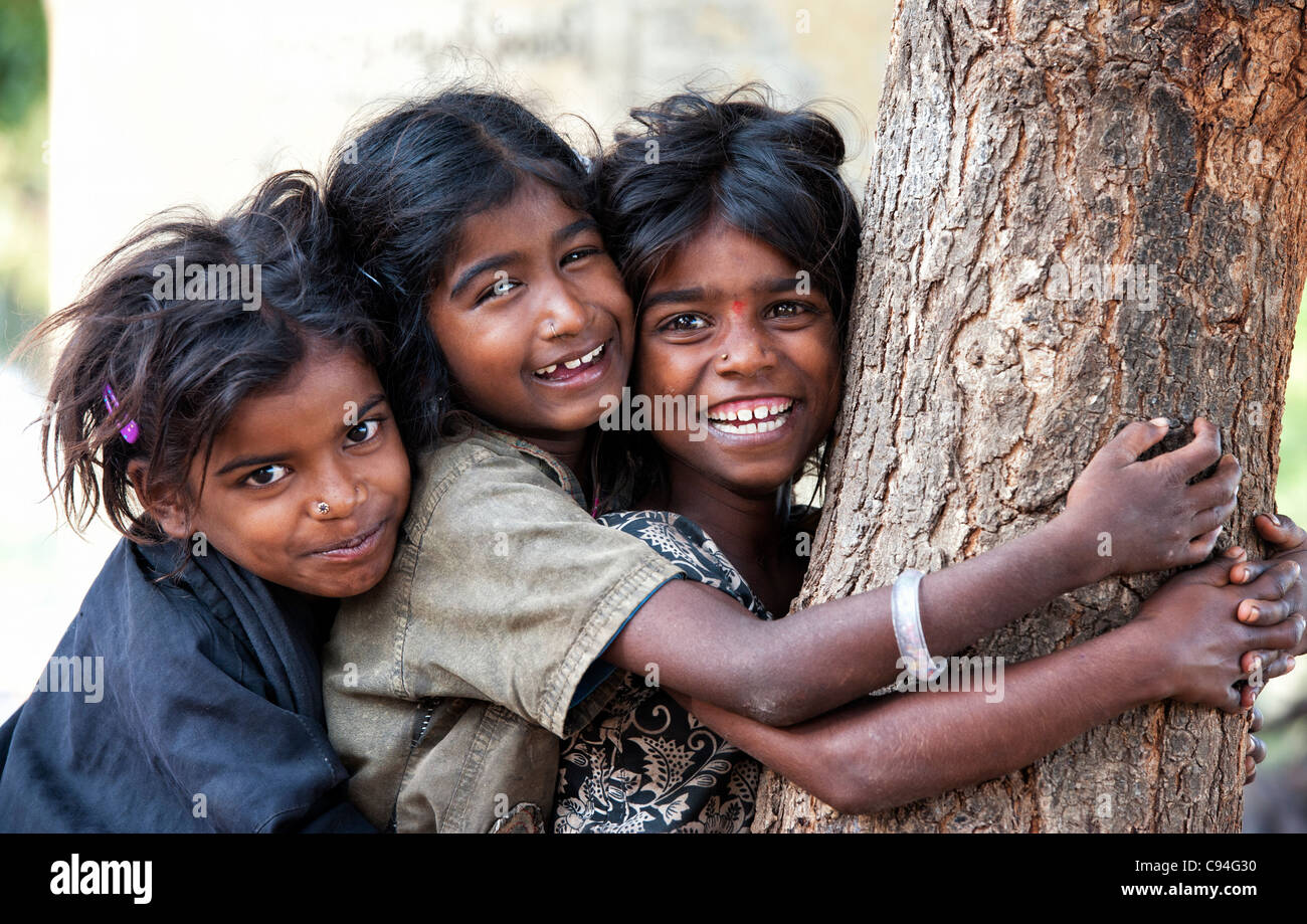 Poor Indian nomadic beggar girls laughing whilst hugging a tree and ...