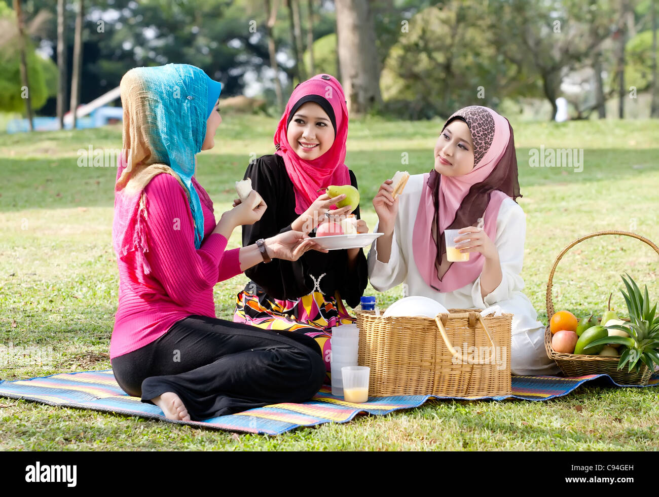 Young muslim woman wearing scarf while relaxing and eating with friends ...