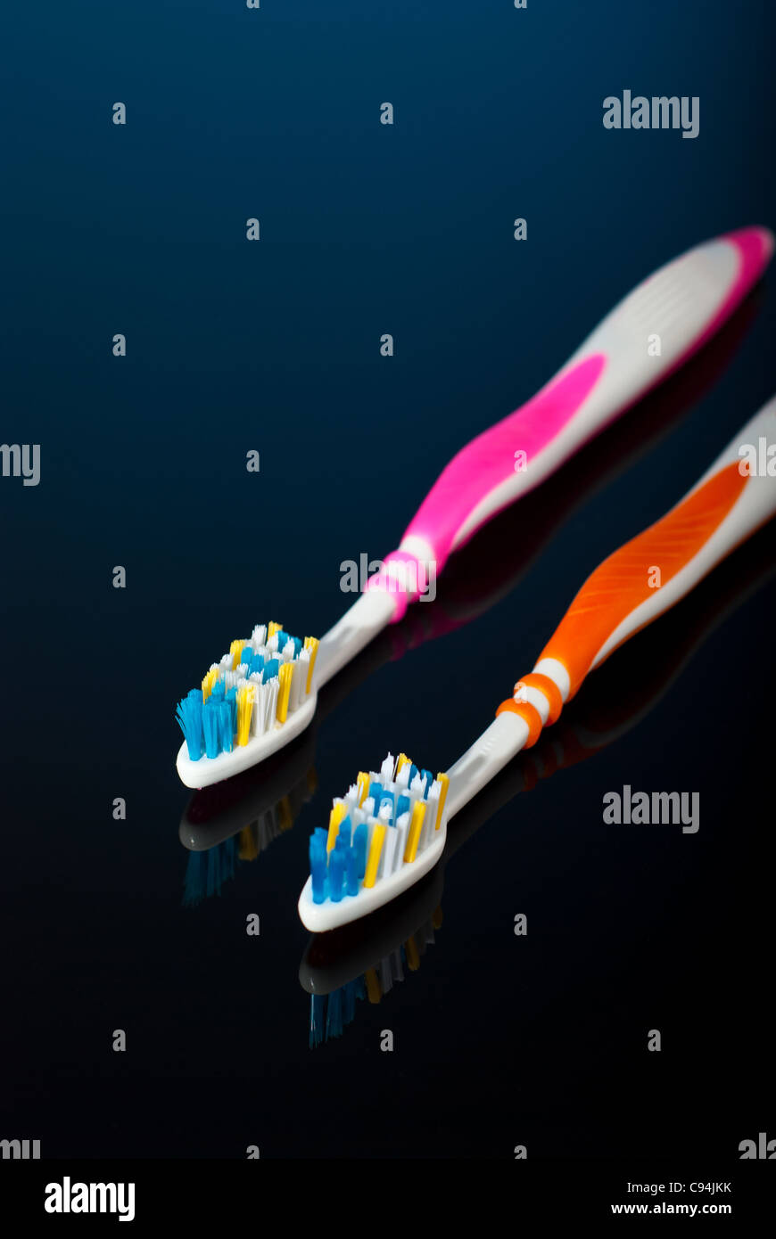 Colorful tooth brushes with reflection on black background with blue ...