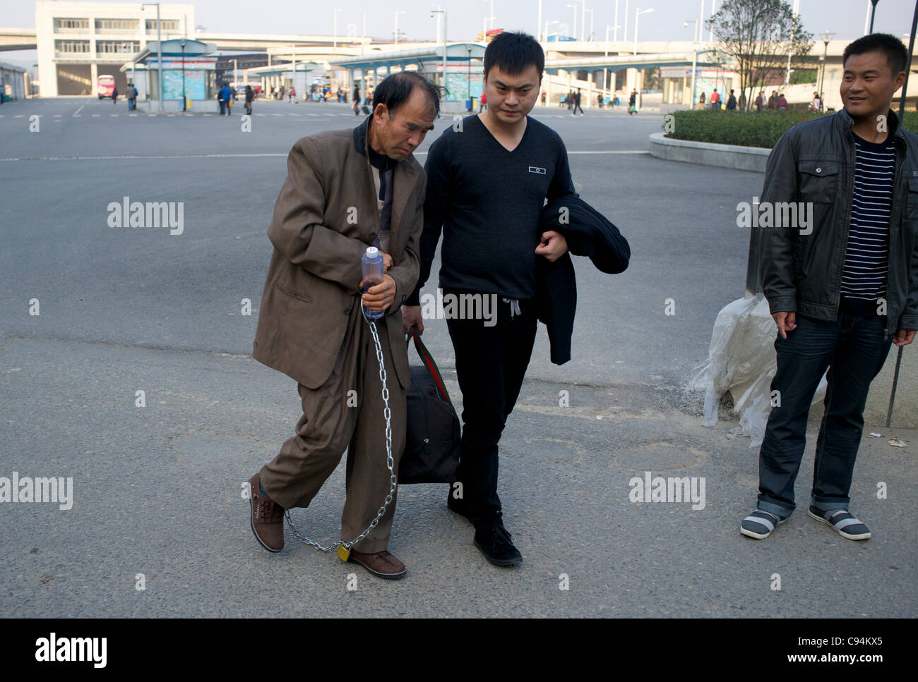 A Chinese man is taken away in handcuffs and shackles by a policeman in ...