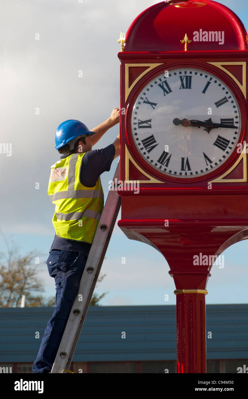 Workman fitting the town clock after refurbishment, in Villemomble ...