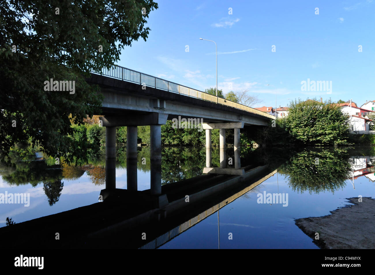 Modern concrete bridge across a river with its reflection and a blue ...