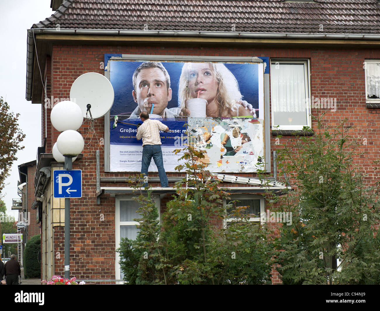 Billsticker working at a billboard on a house in Winsen-Luhe, Lower ...