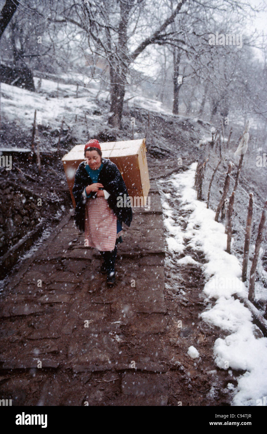 Greek woman carrying a large new television on her back in the small ...