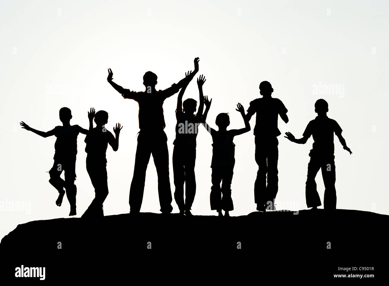Silhouette of young Indian boys jumping on a rock against the sun ...