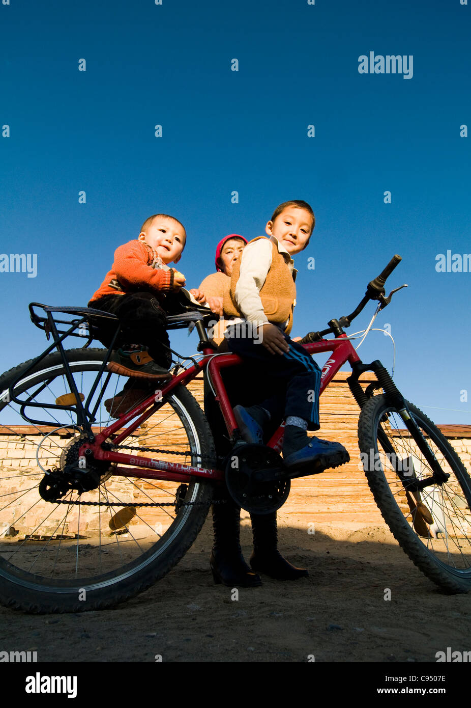 Siblings riding their bicycle with their grandmothers help Stock Photo ...