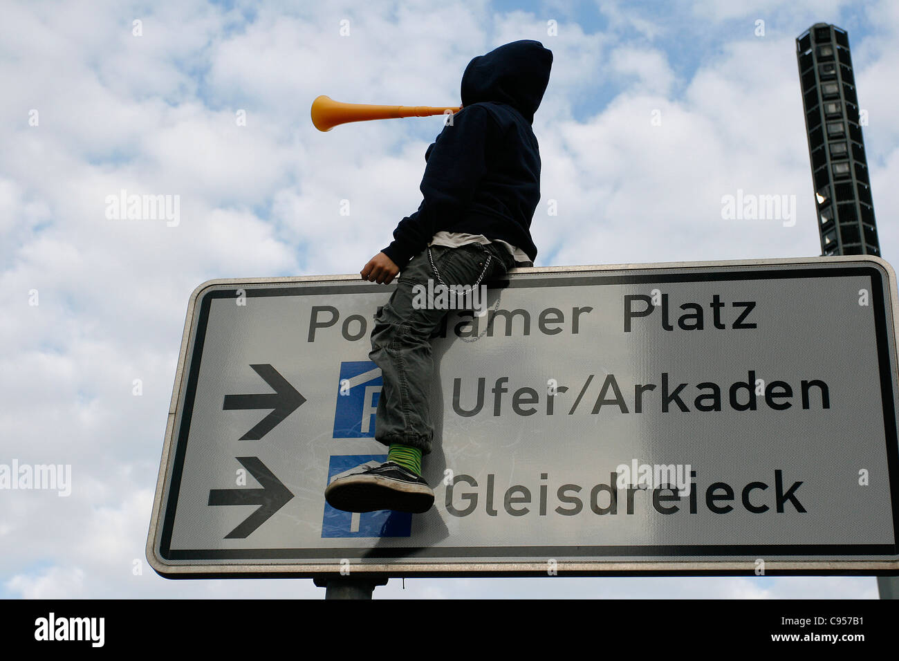 A boy is playing trumpet sitting on a traffic sign from the Potsdamer ...