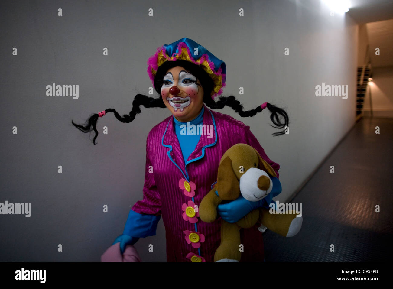 A female clown walks backstage as she holds a teddy bear during the ...