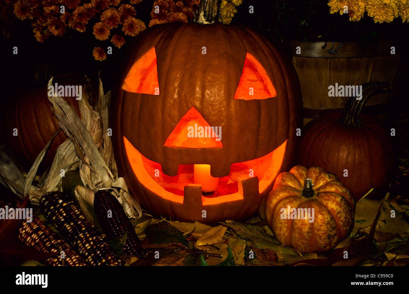 Closeup autumn farm front door display carved pumpkin face with candle ...